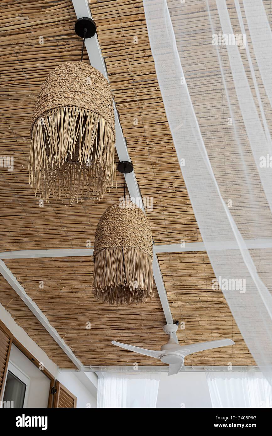 Two woven, tropical-style pendant lamps hanging from a ceiling with a ...