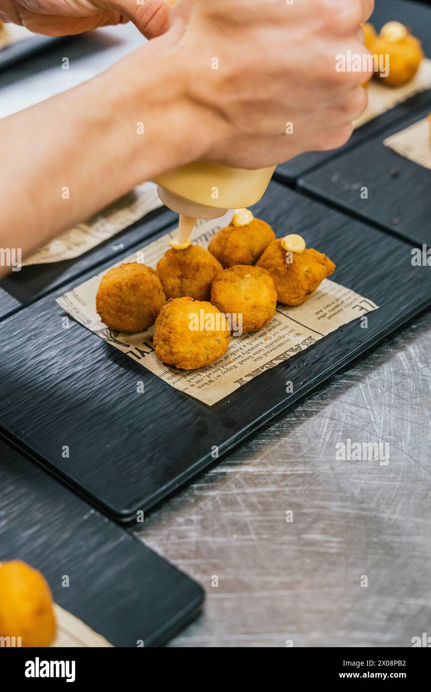 Anonymous chef hands meticulously drizzle a creamy sauce on golden ...