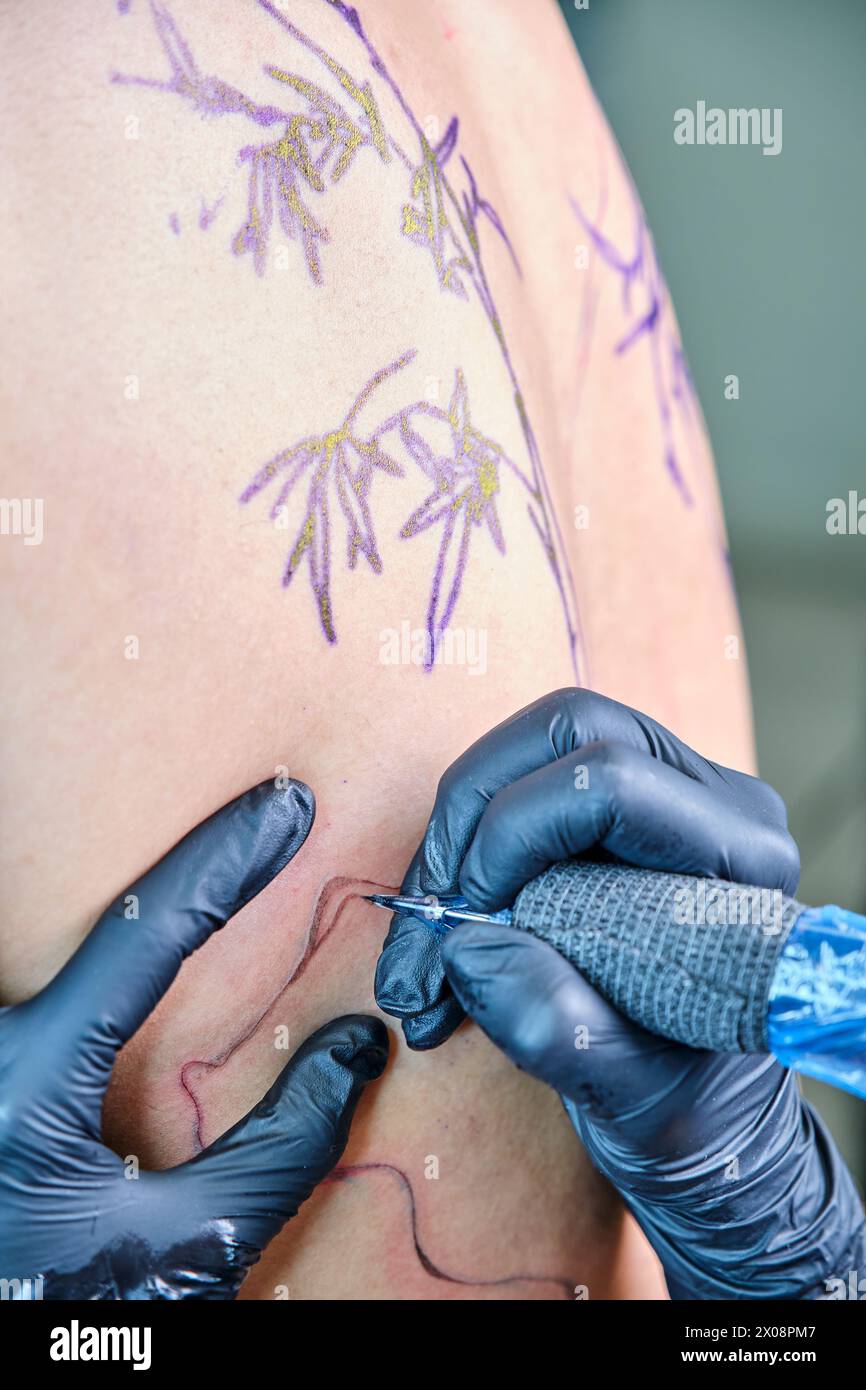 Cropped unrecognizable tattoo artist carefully inks a design on a ...