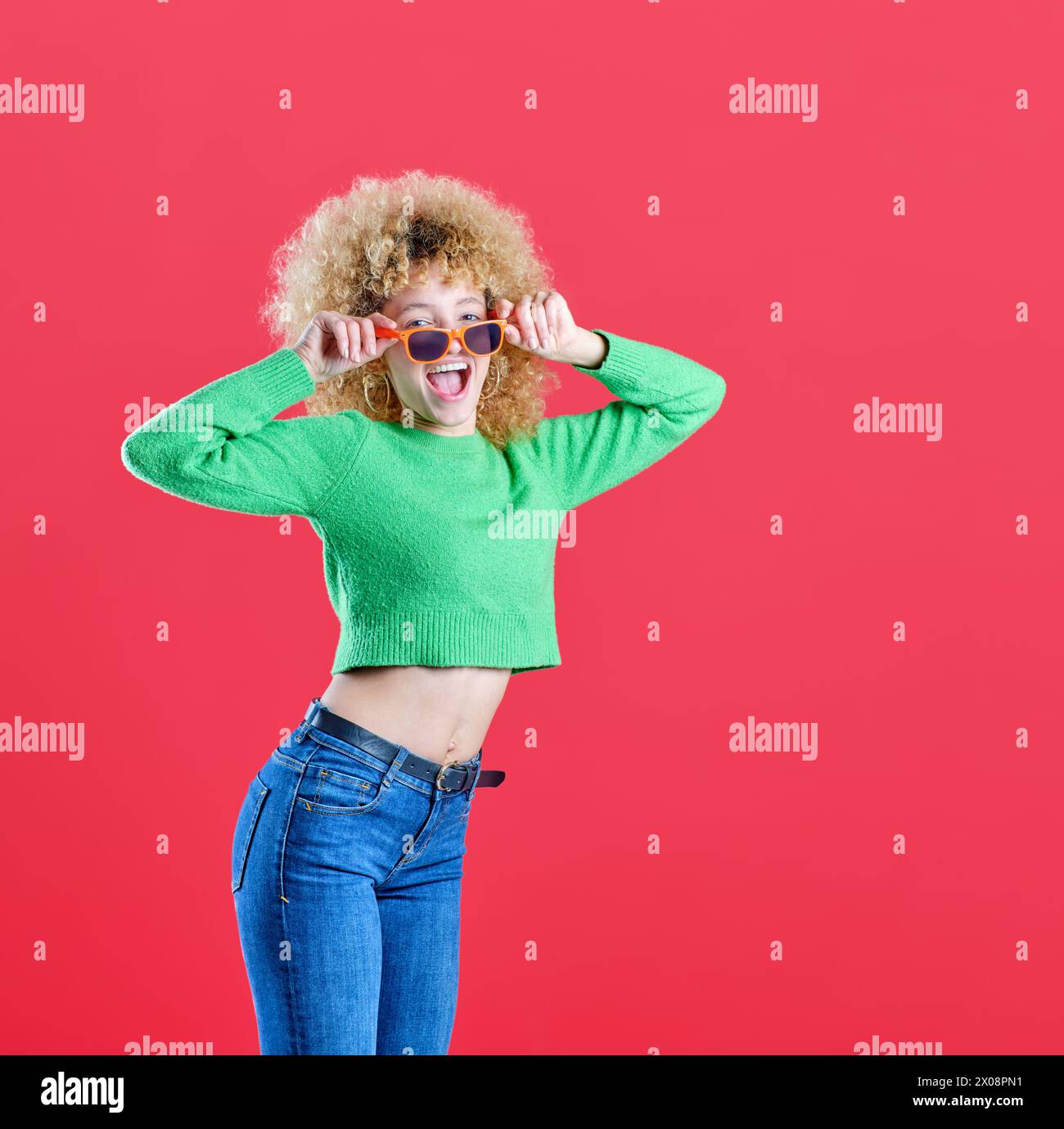 An exuberant woman with curly hair adjusts her sunglasses and laughs ...