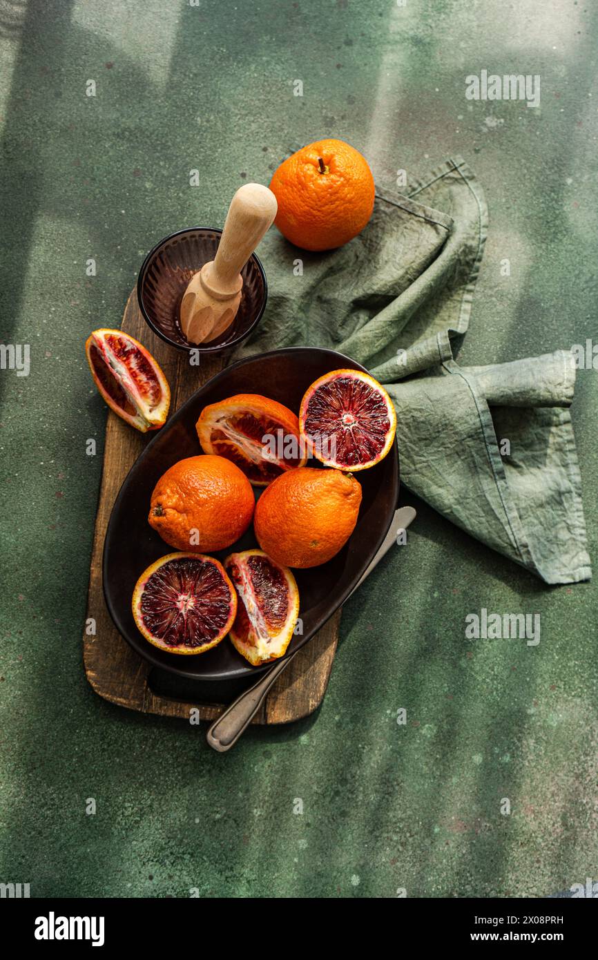 Citrus still life with whole and halved blood oranges on a rustic setup ...