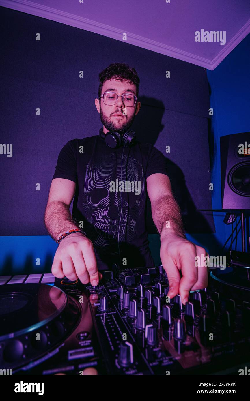 A focused DJ in a dark room enhanced with purple lighting, skillfully ...