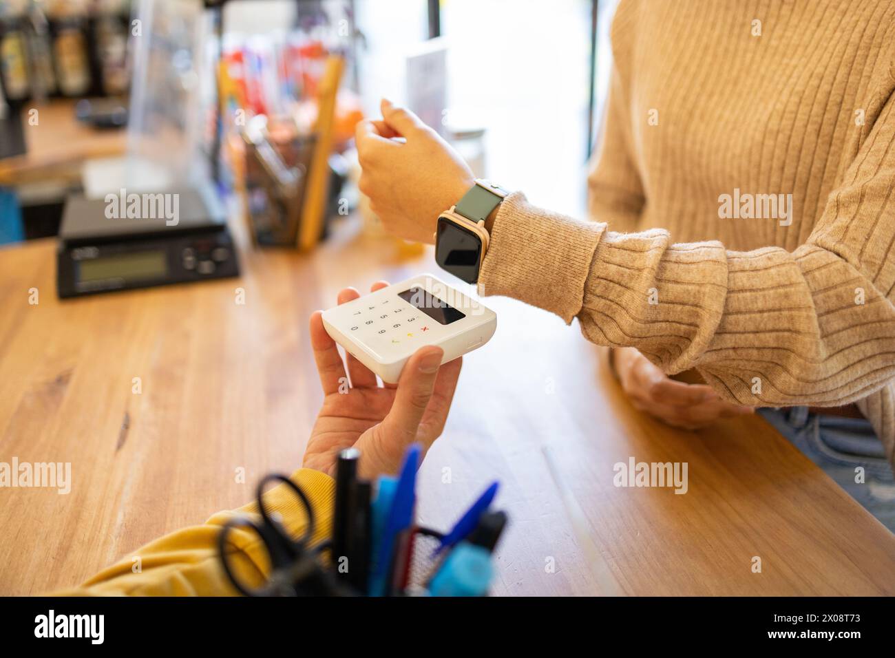 Customer using a smartwatch to perform a contactless payment at a store ...