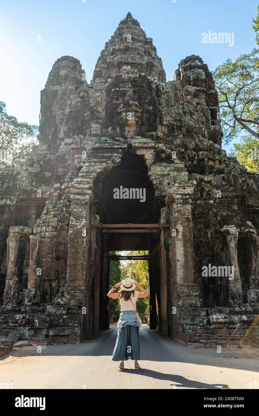 A lone tourist stands before the iconic Angkor Wat temple entrance ...