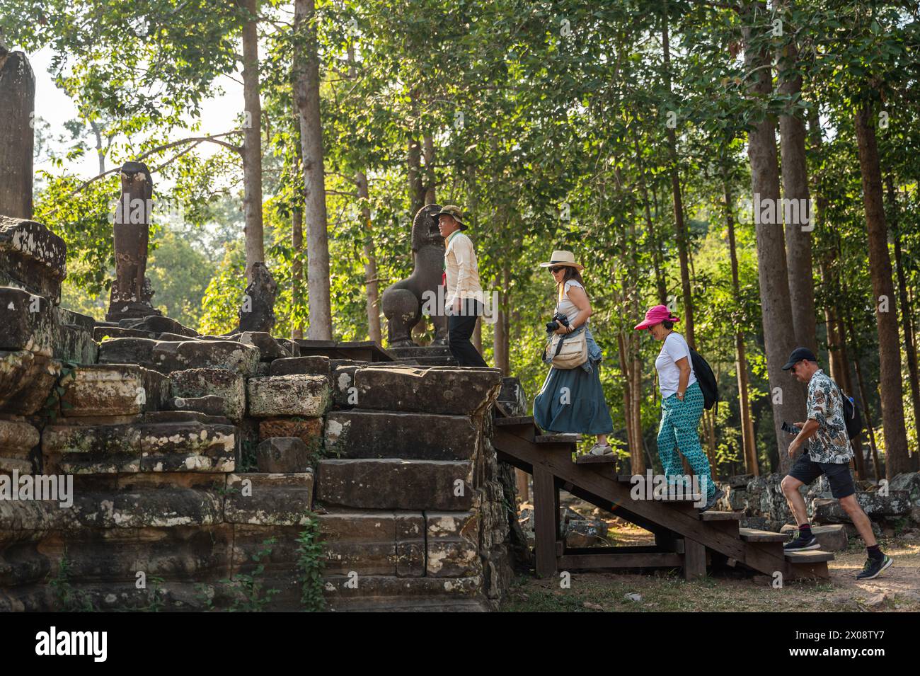 Side view of a group of tourists climbing ancient stone steps amidst ...