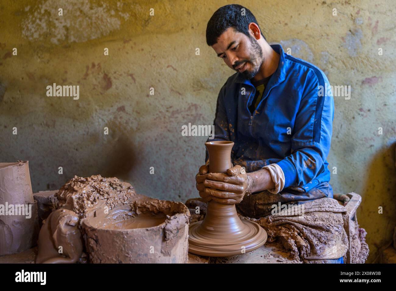 A moroccan artisan carefully molds a clay vase on a spinning wheel in a ...