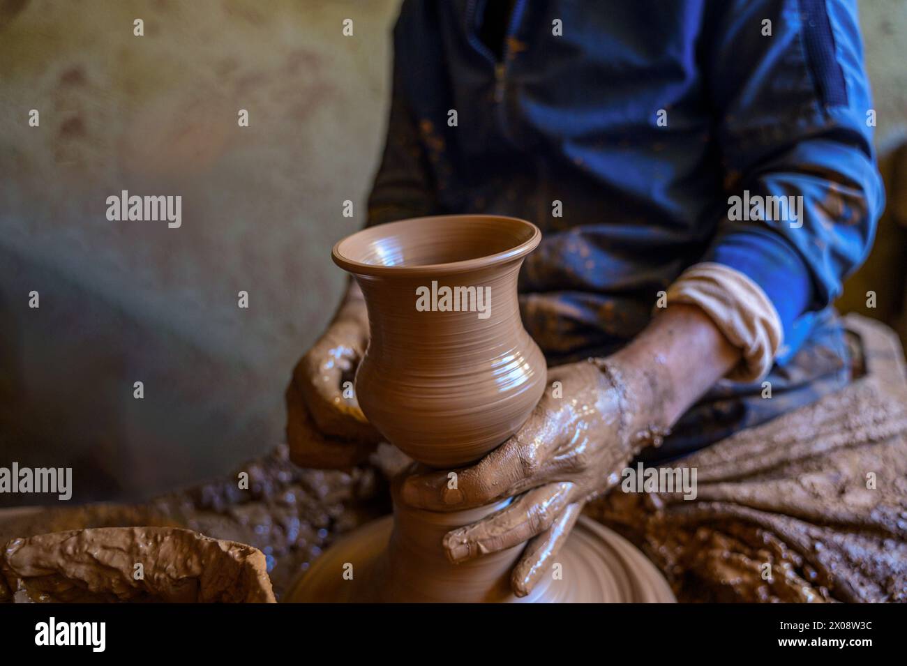 An unrecognizable artisan crafts a traditional clay pot on a pottery ...
