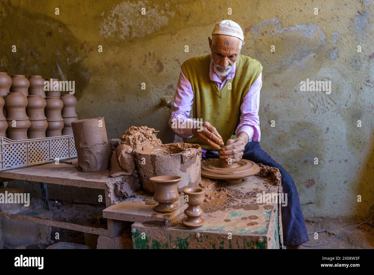 An experienced potter shapes clay on a pottery wheel, surrounded by ...