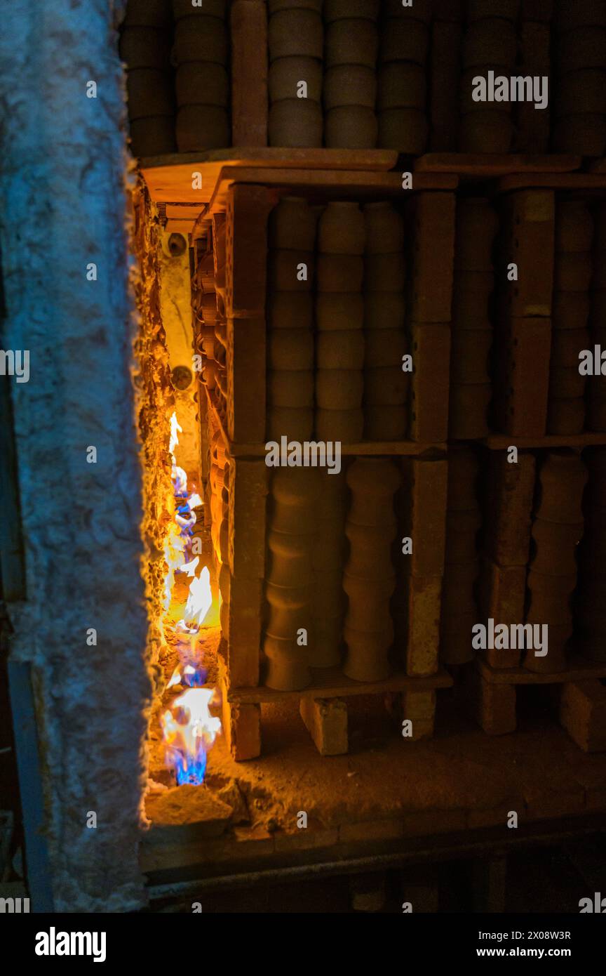 The image captures the vibrant blue flames of a gas-fired kiln ...