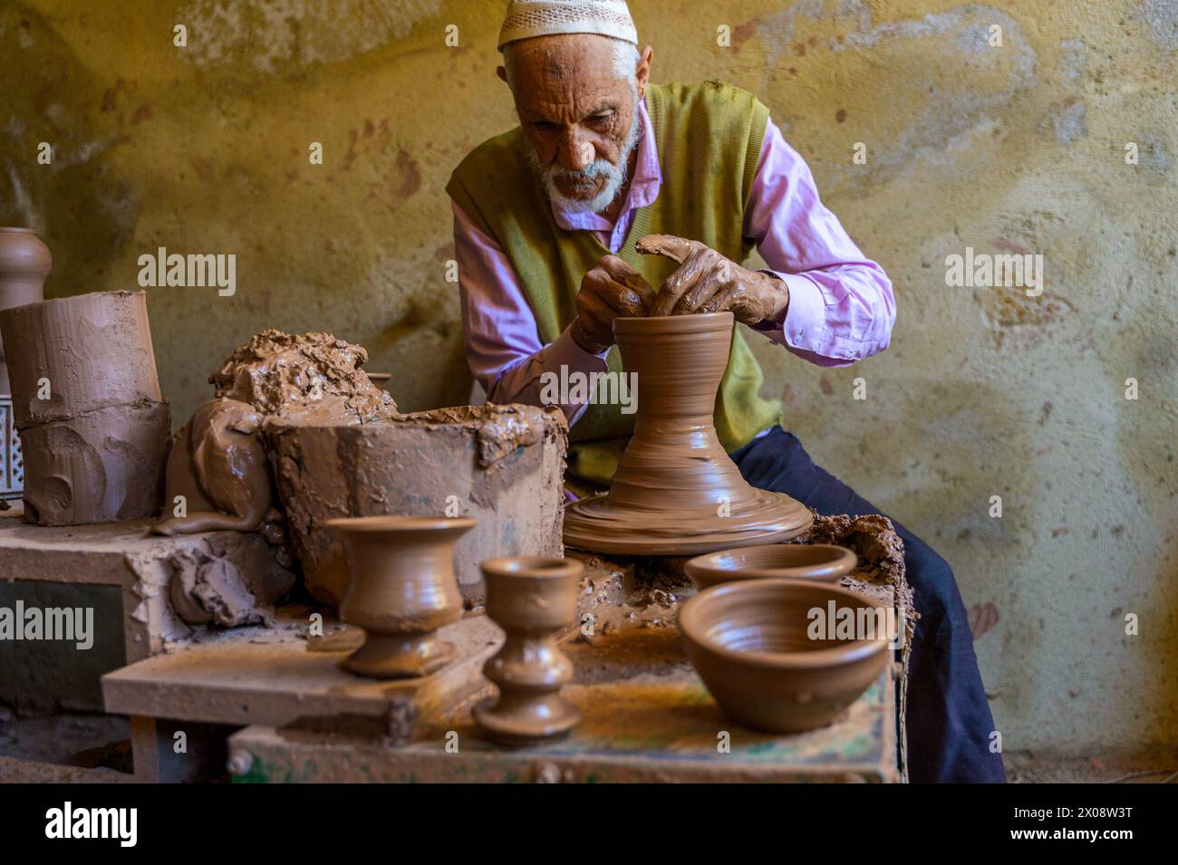 An elderly potter shapes clay on a wheel, creating traditional ceramics ...