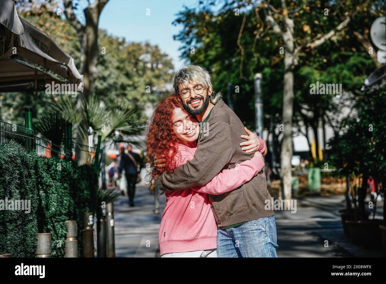 A joyful couple shares a heartfelt hug on a city sidewalk, surrounded ...