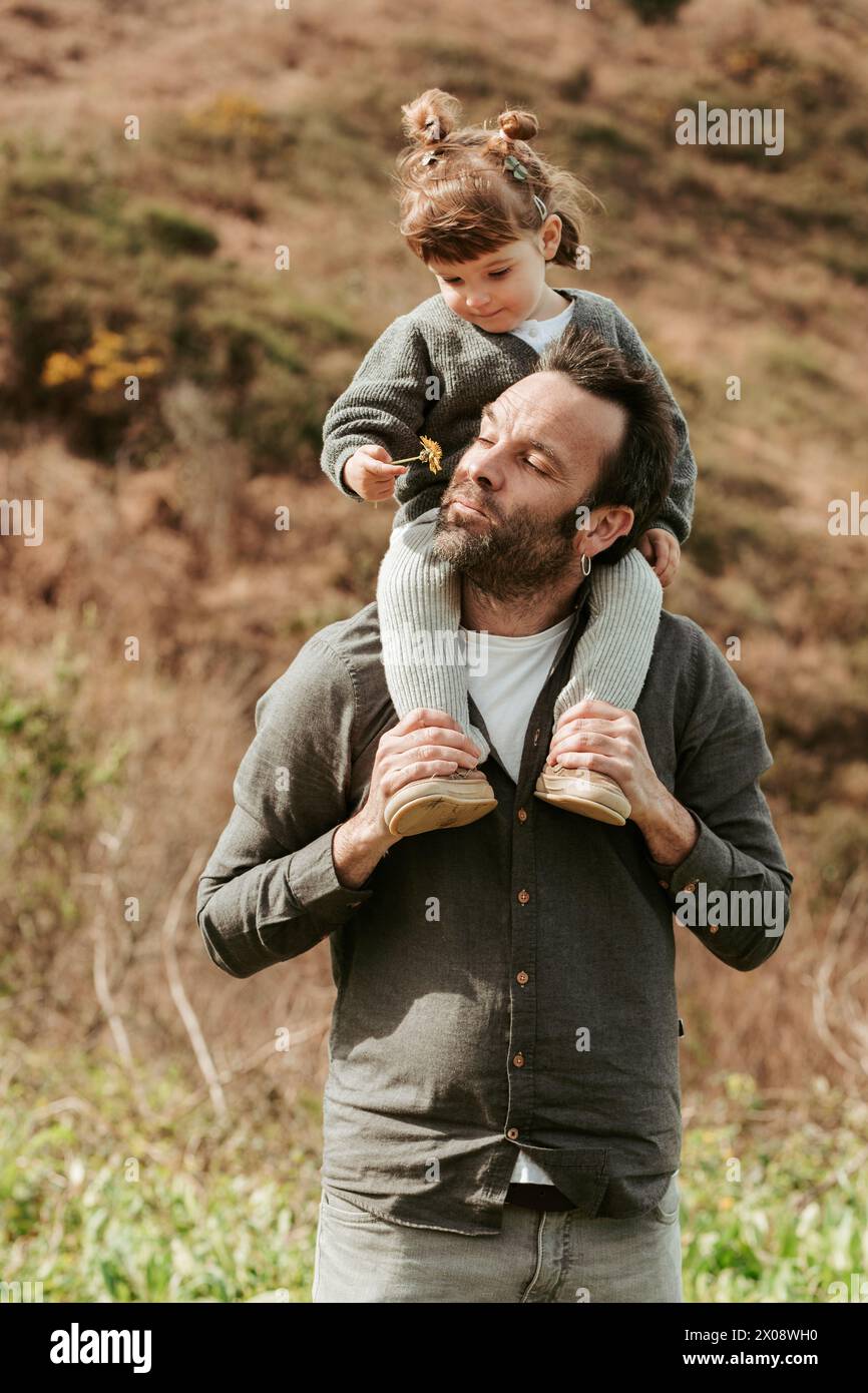 A loving moment as a father carries his young daughter on his shoulders ...