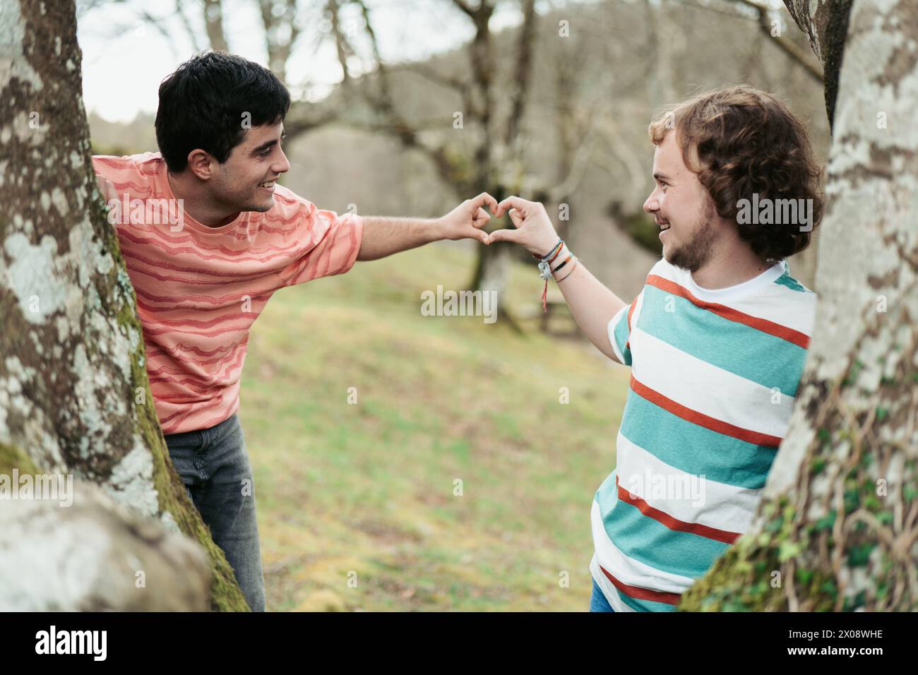 Two joyful men forming a heart shape with their hands, sharing a moment ...