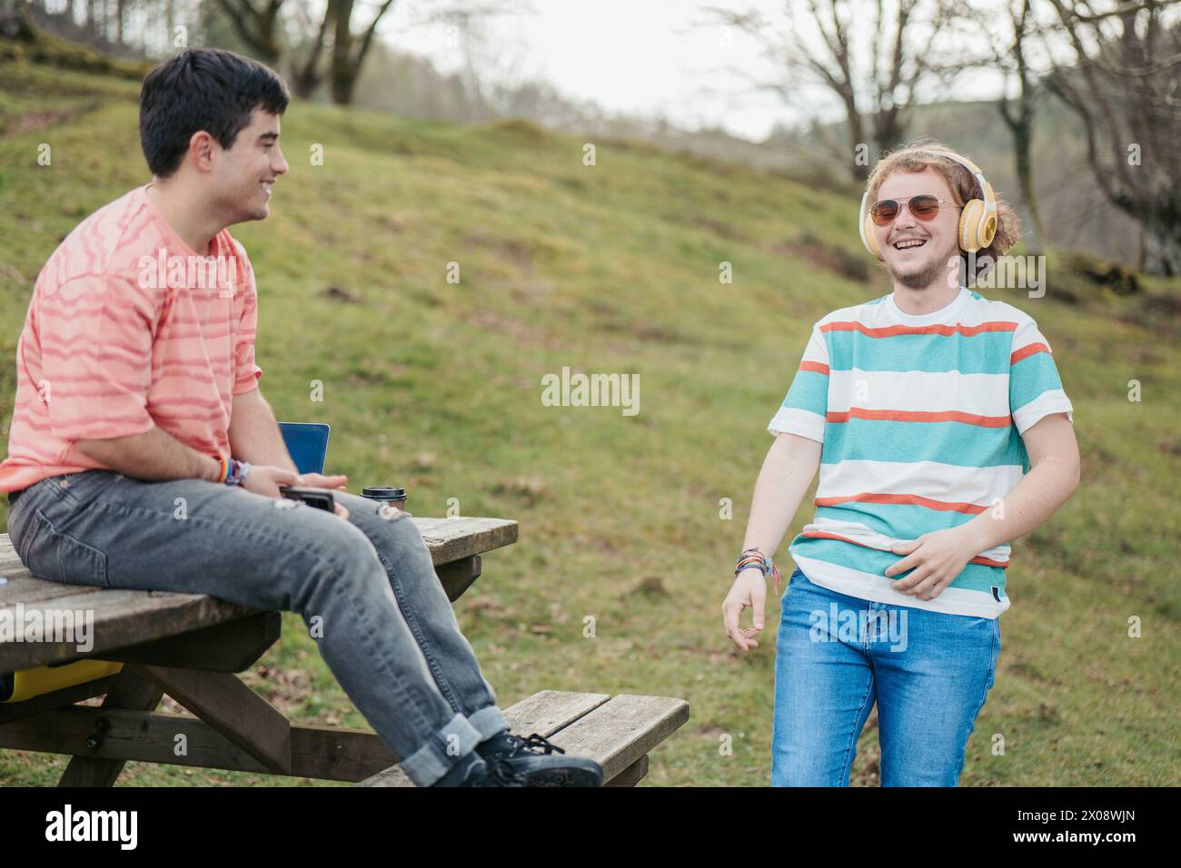 Two happy young men share a laugh while enjoying the outdoors, with one ...