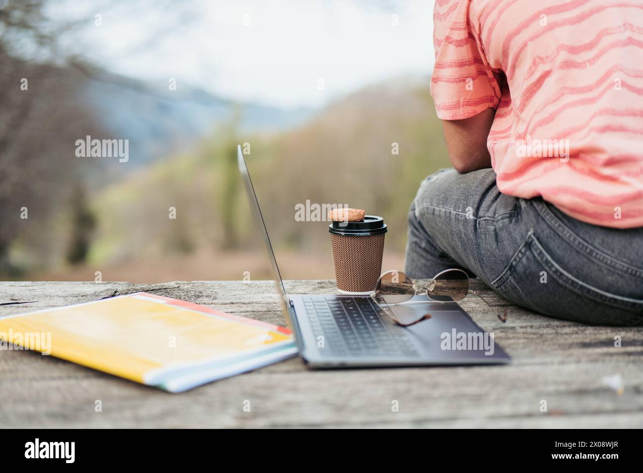 A serene workspace set upon a rustic wooden table outdoors with a ...