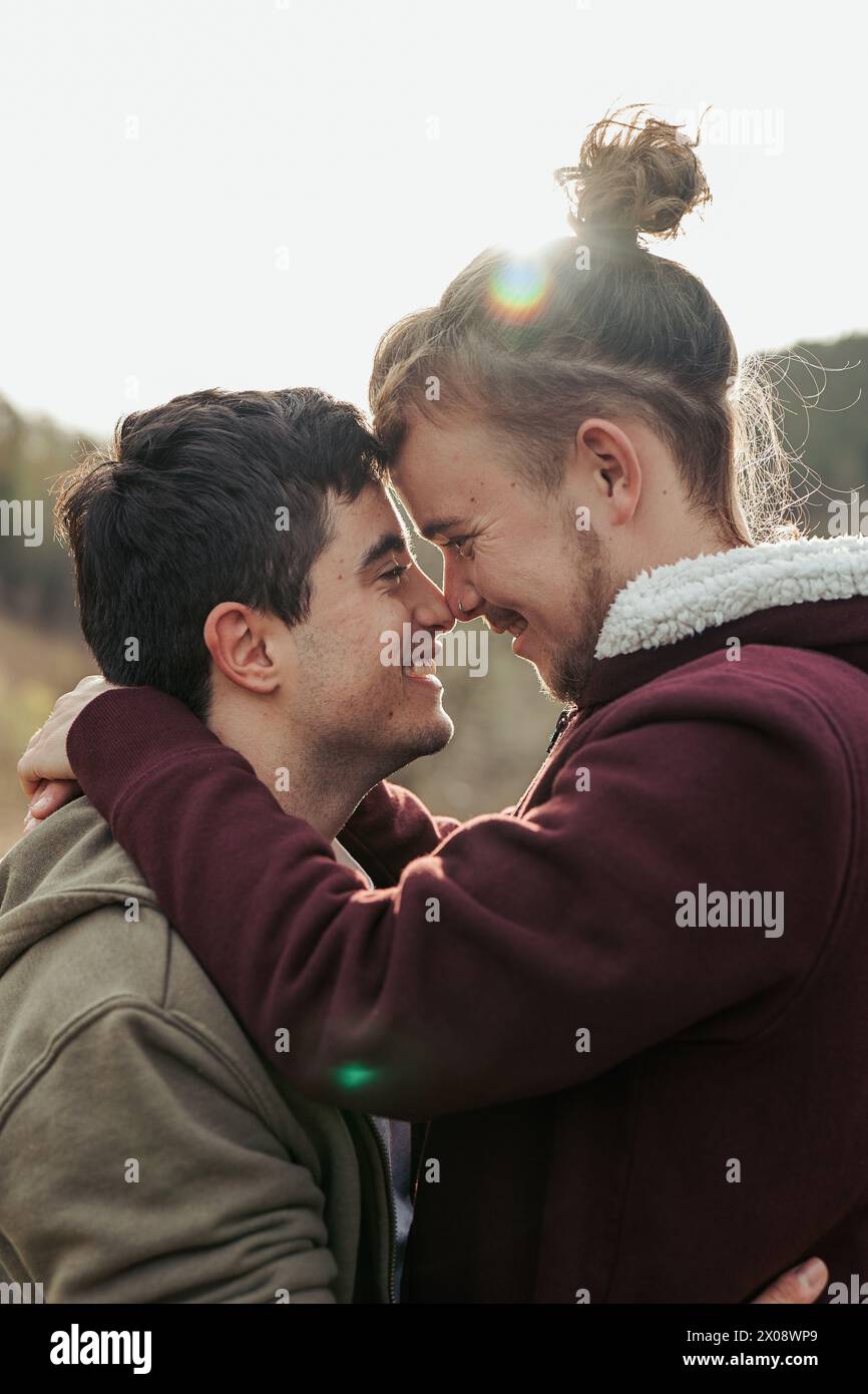 Two men share a joyful embrace, with faces close together and smiles ...