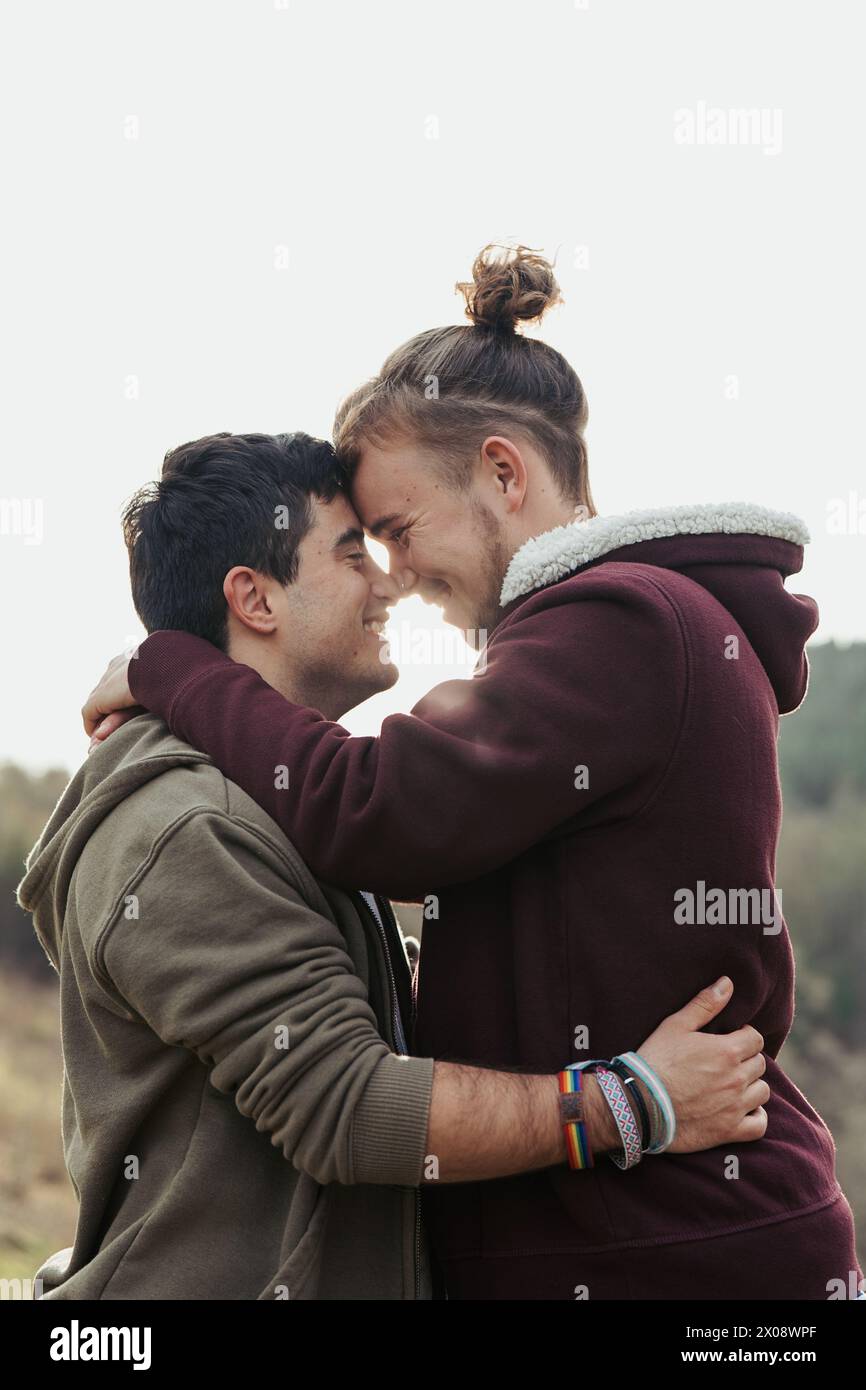 Two men share a joyful embrace, with faces close together and smiles ...