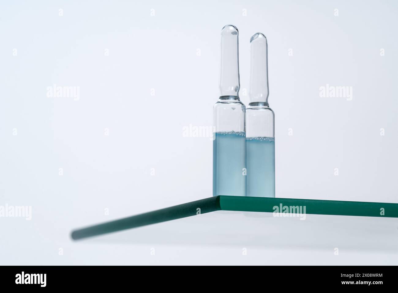 Glass ampoules filled with blue serum, designed for skin and hair care ...