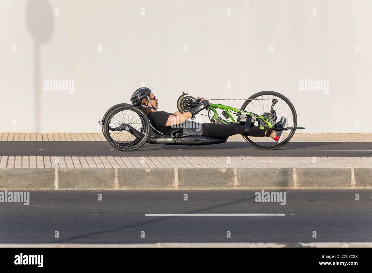 A focused female athlete in racing gear operates a hand-cranked ...