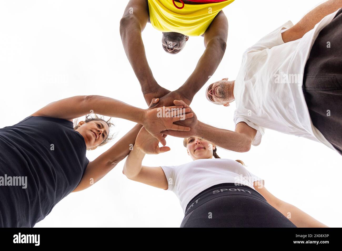 From a unique low angle, a basketball team's hands join together above ...