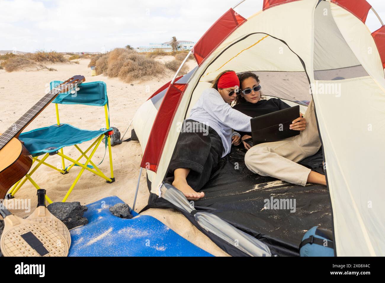 A couple relaxes inside their tent with a digital tablet, comfortably ...
