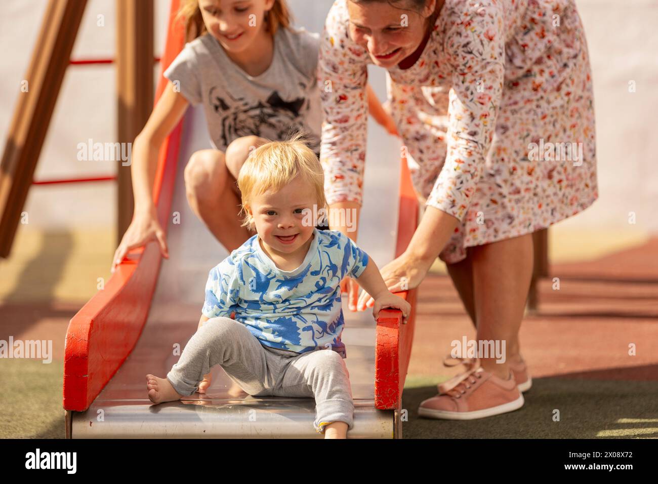 Family with a child with Down syndrome enjoy fun time on playground ...