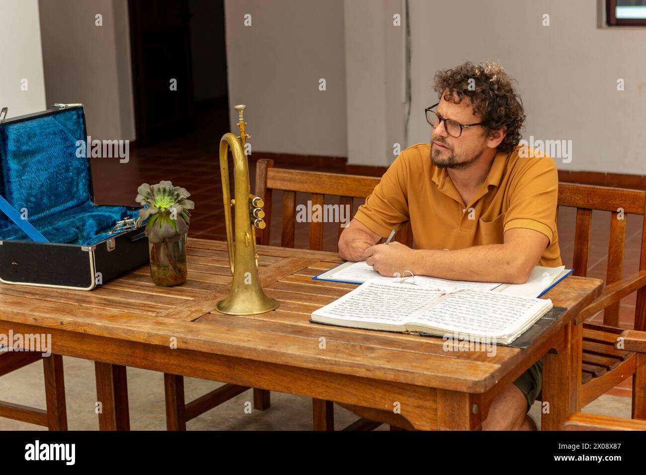 A one-armed male trumpeter in a home courtyard engrossed in writing ...