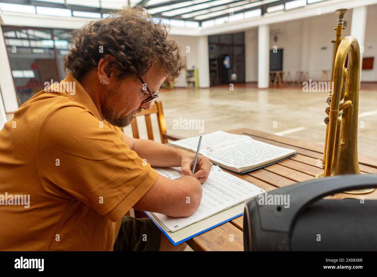 Side view of a man with one arm writes music while sitting next to his ...