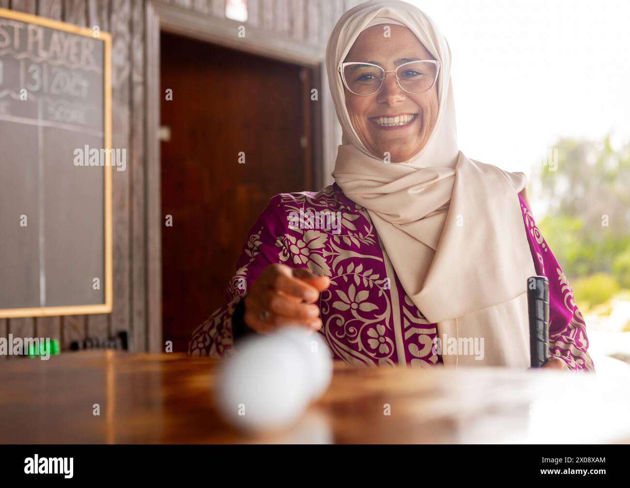 Cheerful muslim woman in hijab looking at camera while playing mini ...