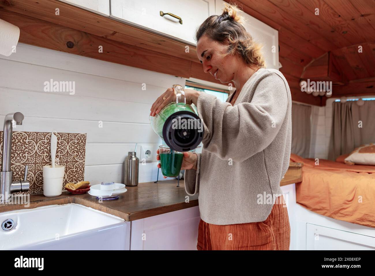 Woman pours a drink inside a well-equipped van home, depicting a family ...