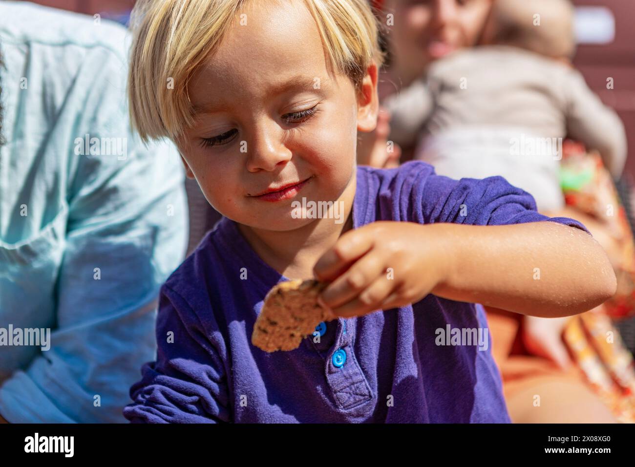 A close-up of a toddler boy sharing a cookie, with his van-life family ...