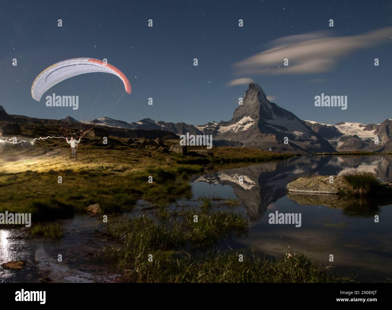 A paraglider takes to the air in the still of the night, with the ...