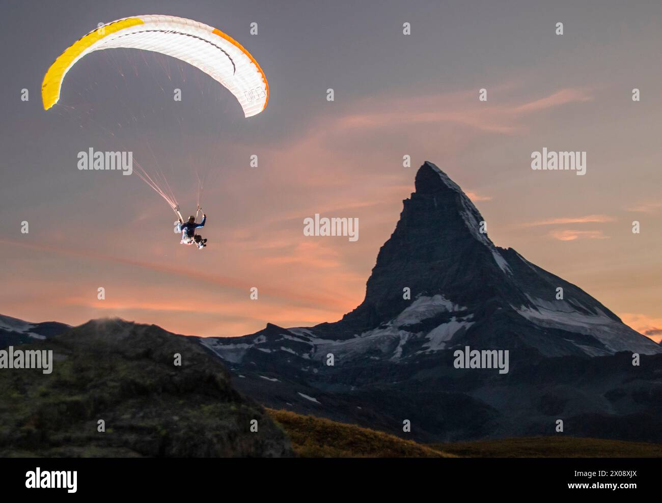A paraglider soars against a scenic sunset backdrop with the majestic ...