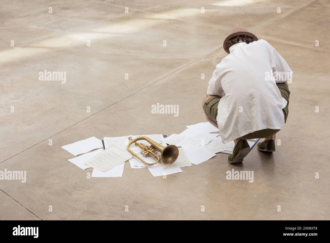 A musician with one arm carefully reviews sheet music while his trumpet ...