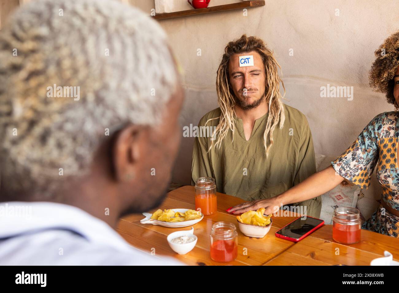 A diverse group of friends enjoys a fun guessing game with sticky notes ...