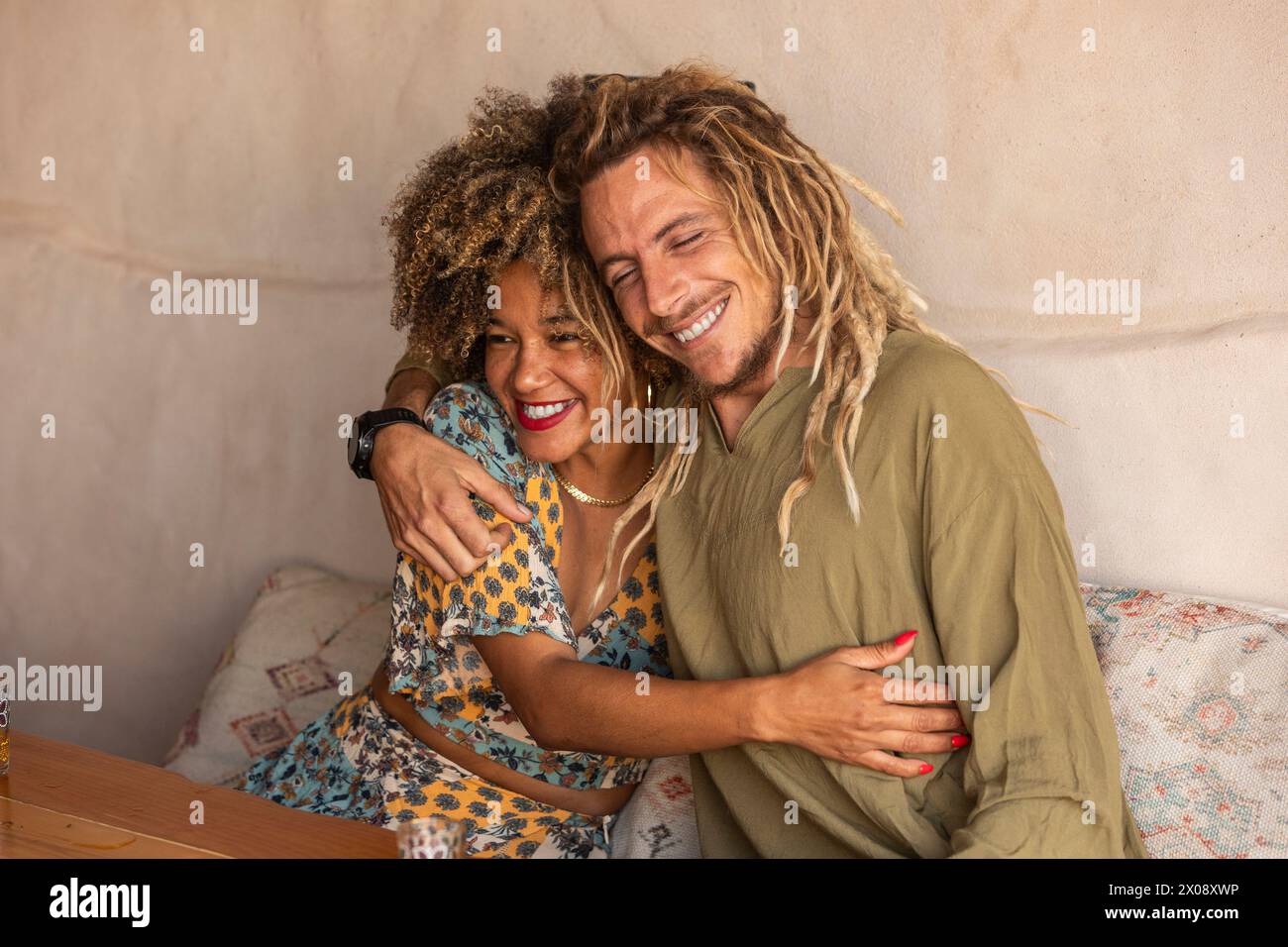 A laughing couple with dreadlocks sharing a warm, affectionate embrace ...