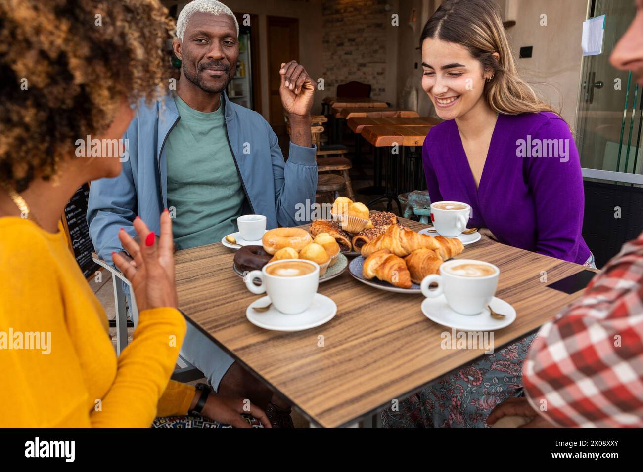A group of friends sharing laughter over a table full of coffee cups ...