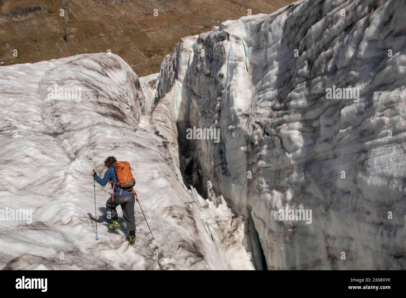 An intrepid explorer with a backpack hikes across the crevassed surface ...
