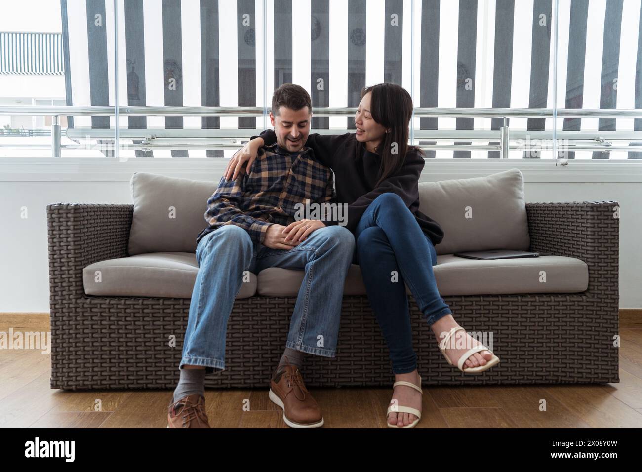 Intimate moment of a joyful couple relaxing together on a sofa in a ...