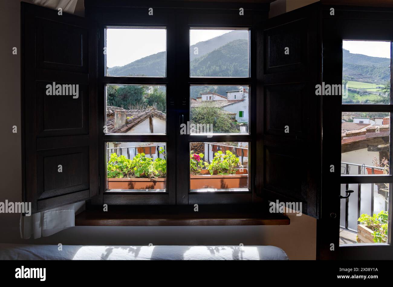 Classic wooden window opening to a beautiful view of Potes, with lush ...