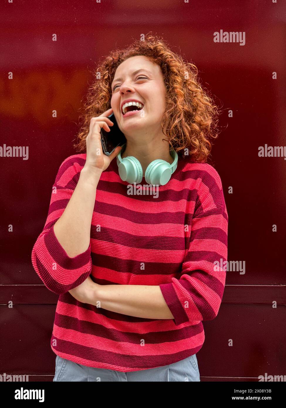 A cheerful redhead woman with curly hair smiles as she talks on the ...