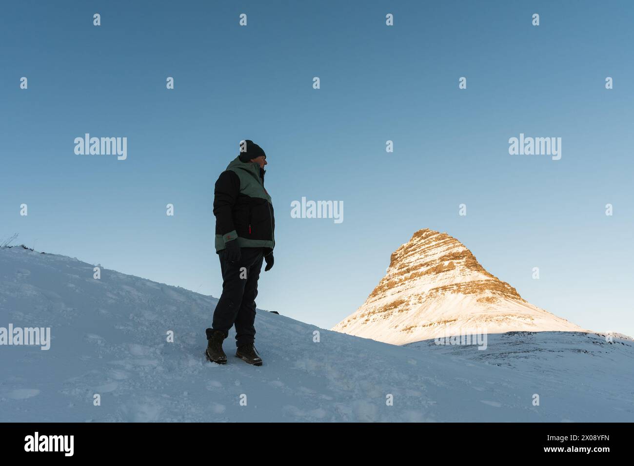 From below of lone explorer stands against the vastness of a snow ...