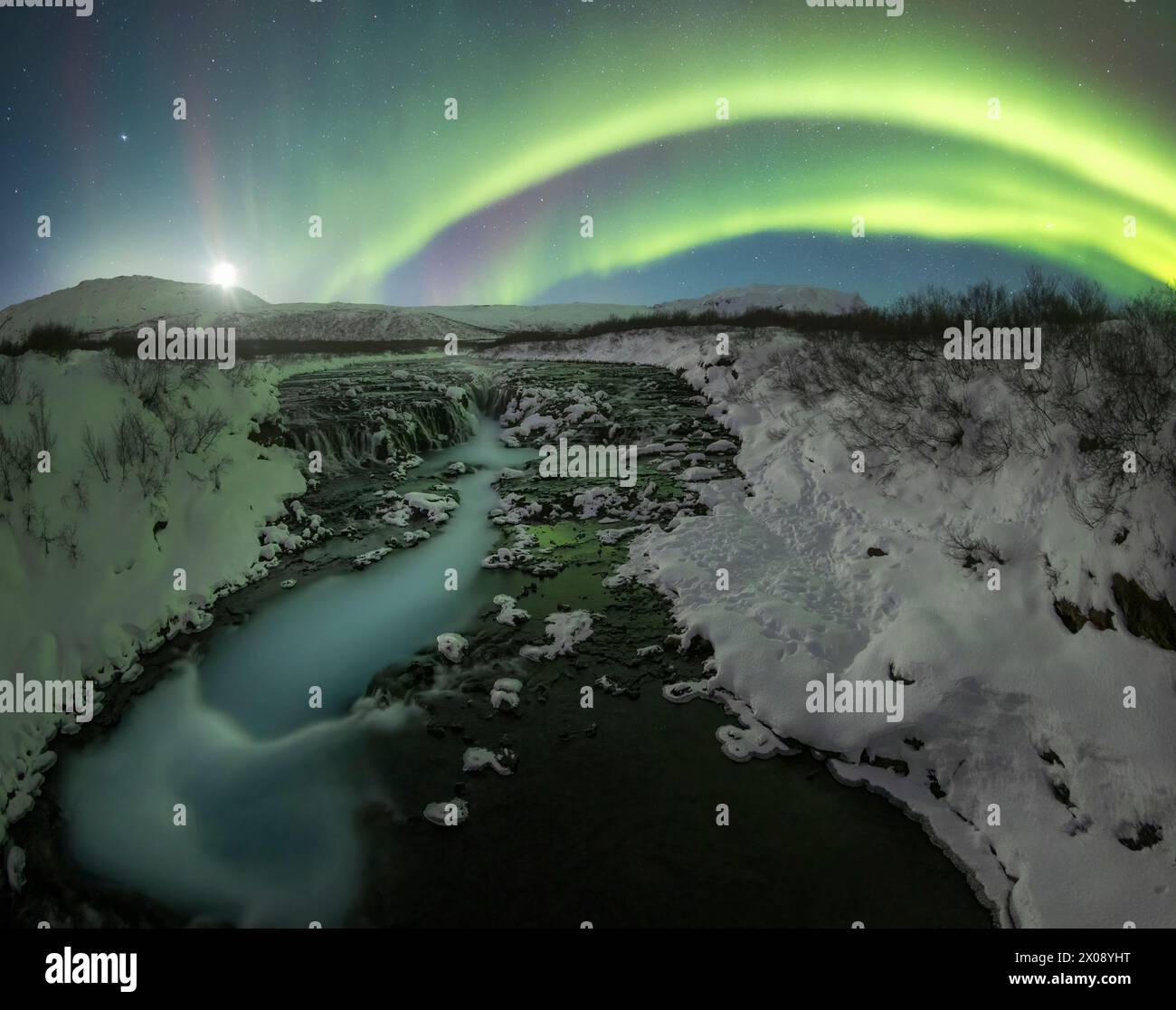 A stunning view of the Northern Lights arcing over a snowy river ...