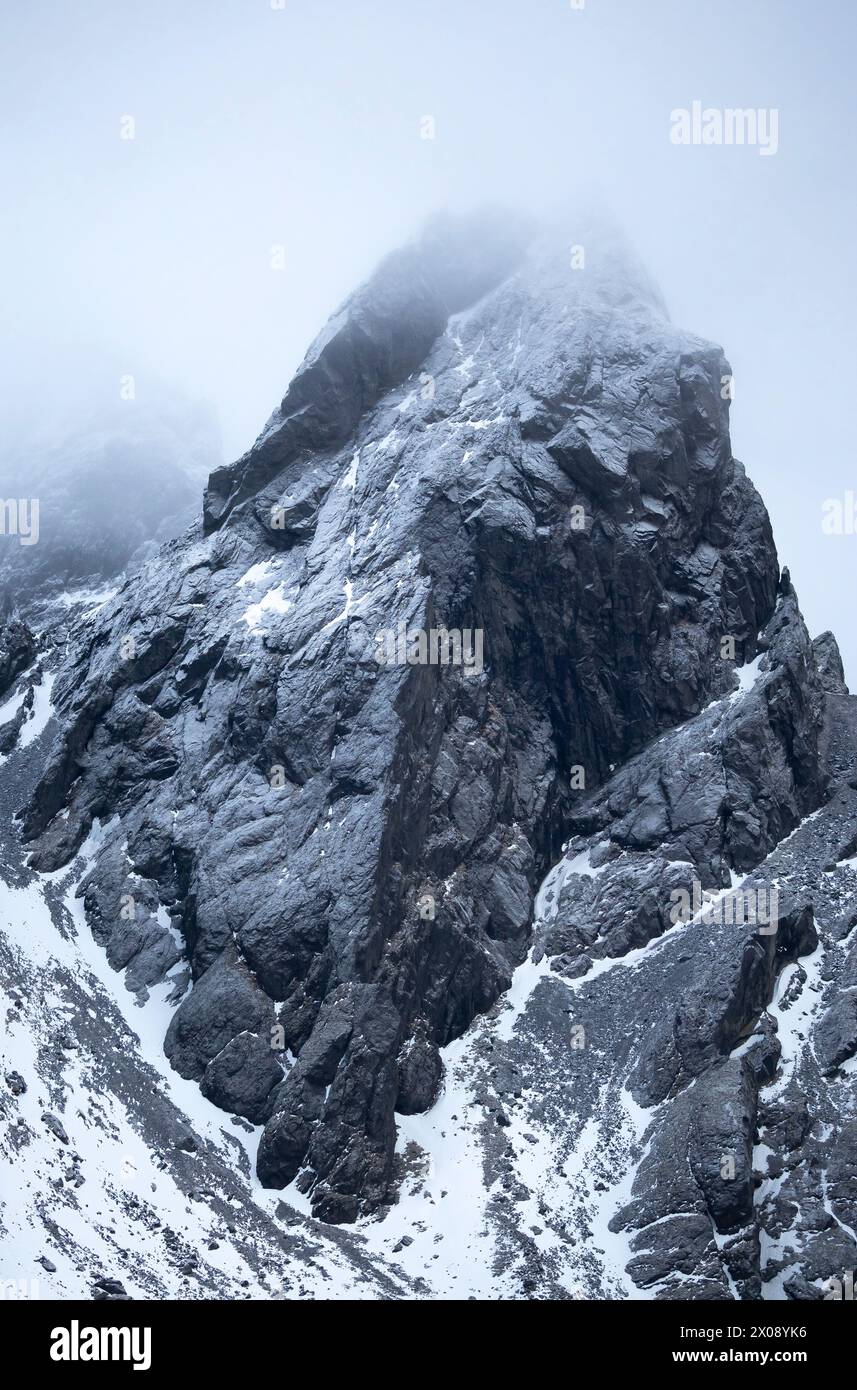 The stunning image captures a grand, fog-shrouded mountain peak in ...