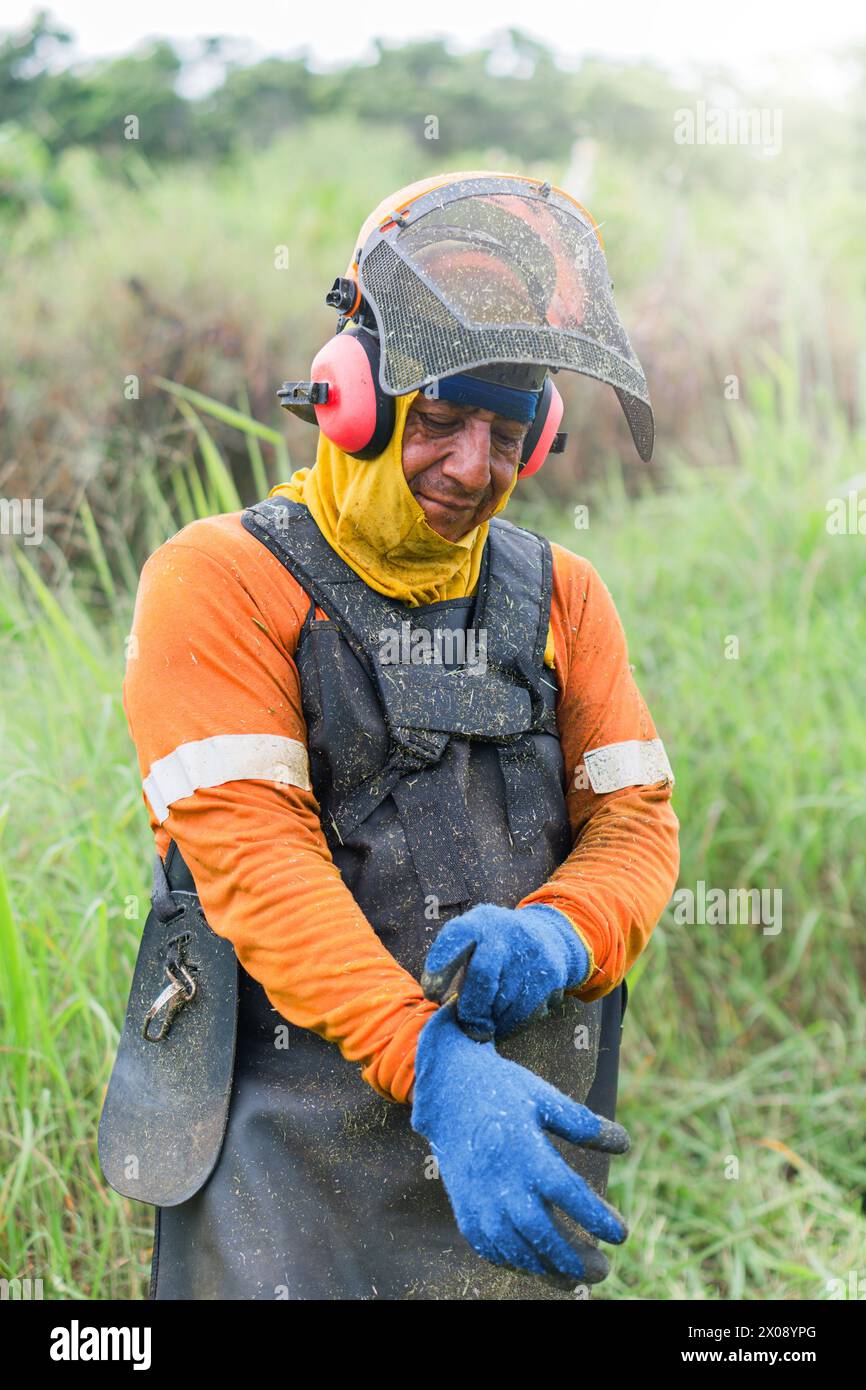 A farmer stands in a lush field, his safety helmet with a visor and ...