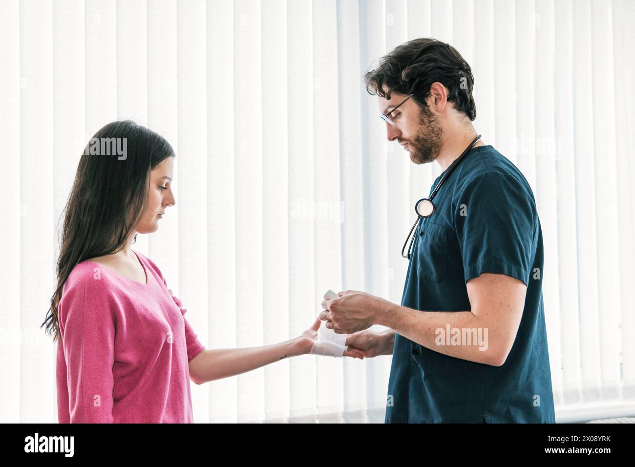 A caring doctor is seen carefully wrapping a bandage around a patient's ...