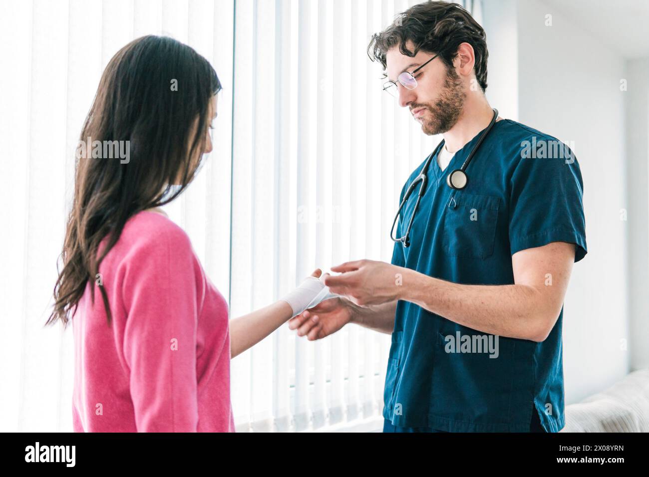 A caring doctor is seen carefully wrapping a bandage around a patient's ...