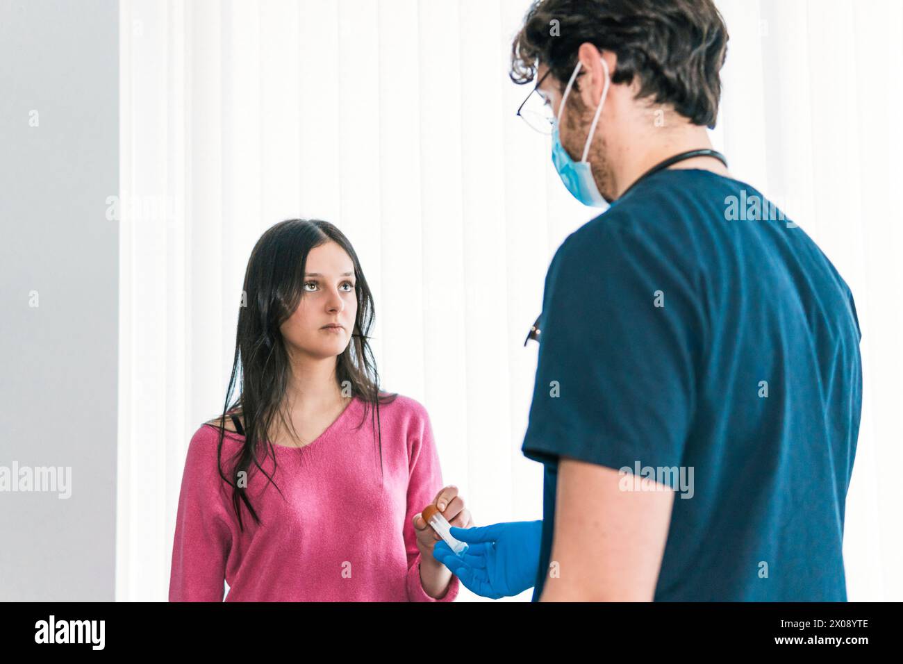 A healthcare professional in blue scrubs prepares a medical device with ...