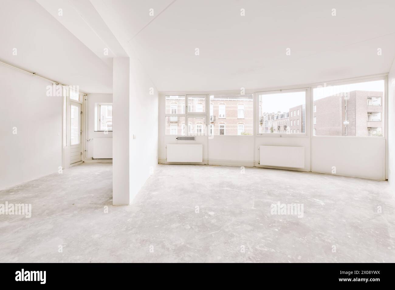 An airy, empty white room featuring large windows allowing for ample ...