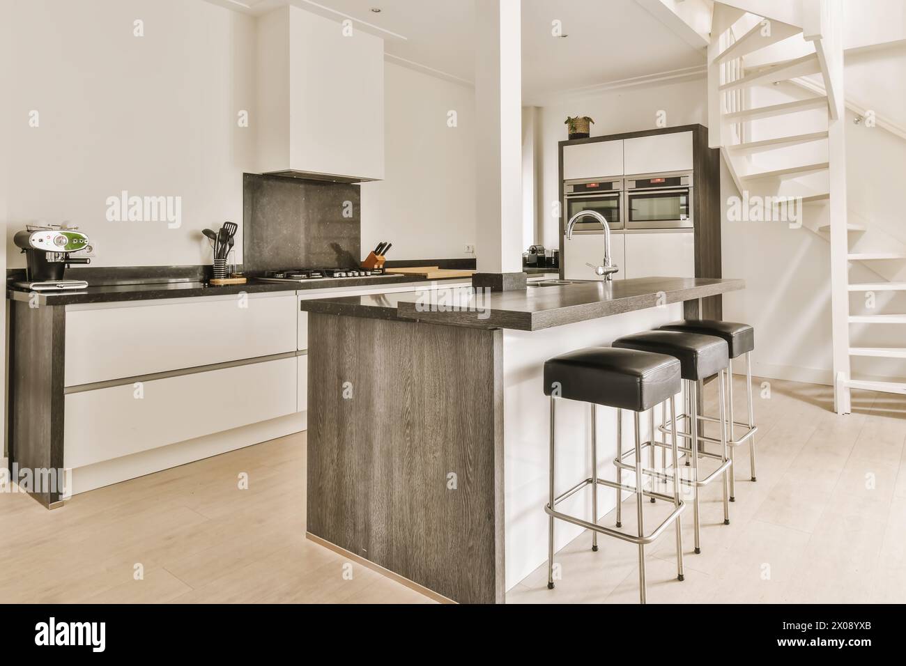 This contemporary kitchen features a sleek island with bar stools and ...